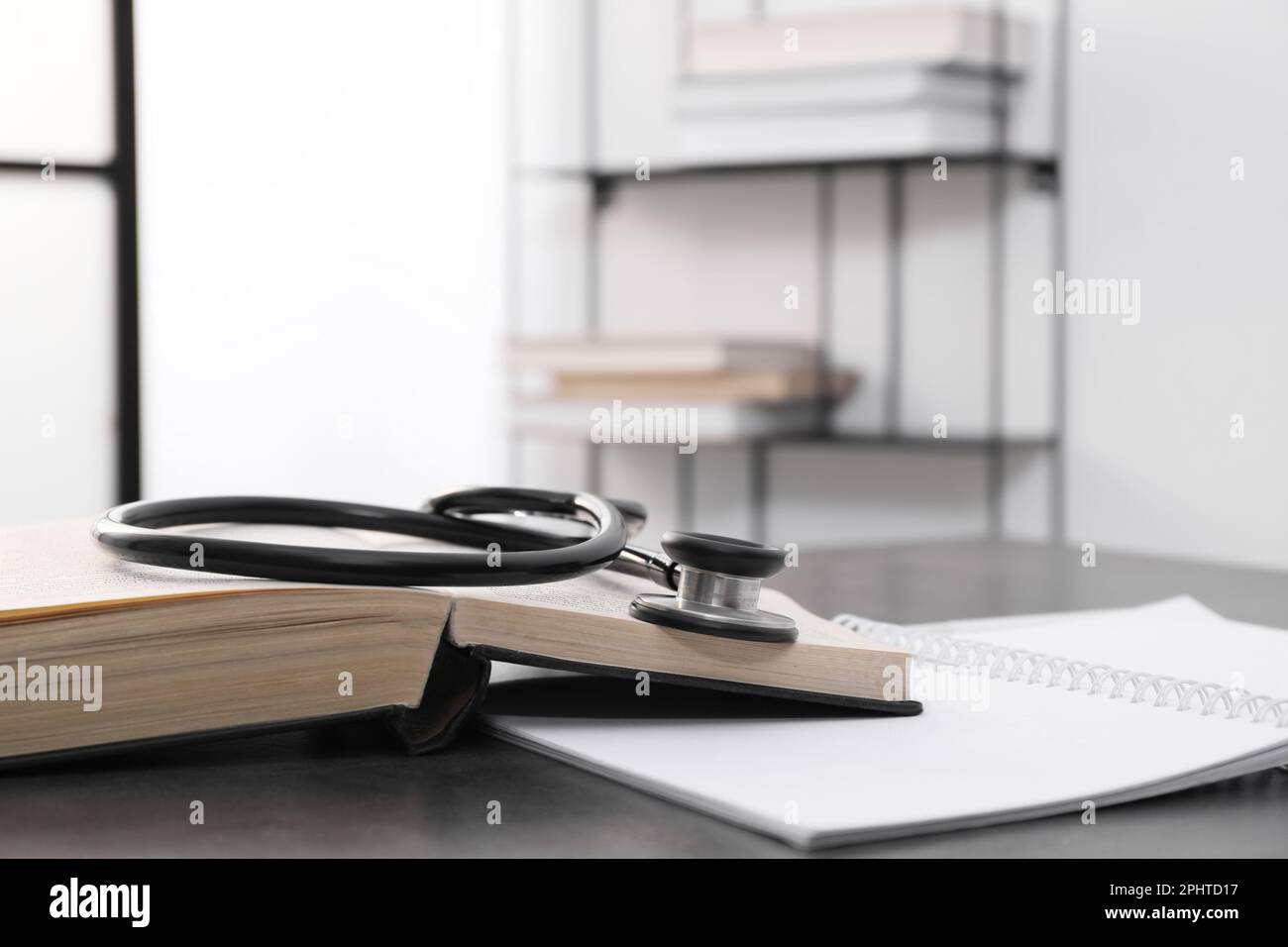 Open student textbook and stethoscope on grey table indoors. Medical ...