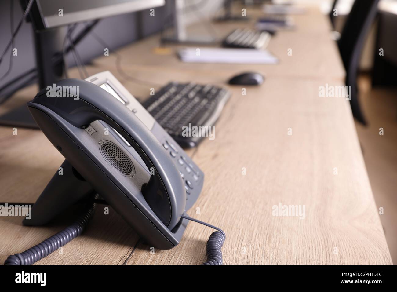 Stationary phone near modern computer on wooden desk in office. Hotline ...