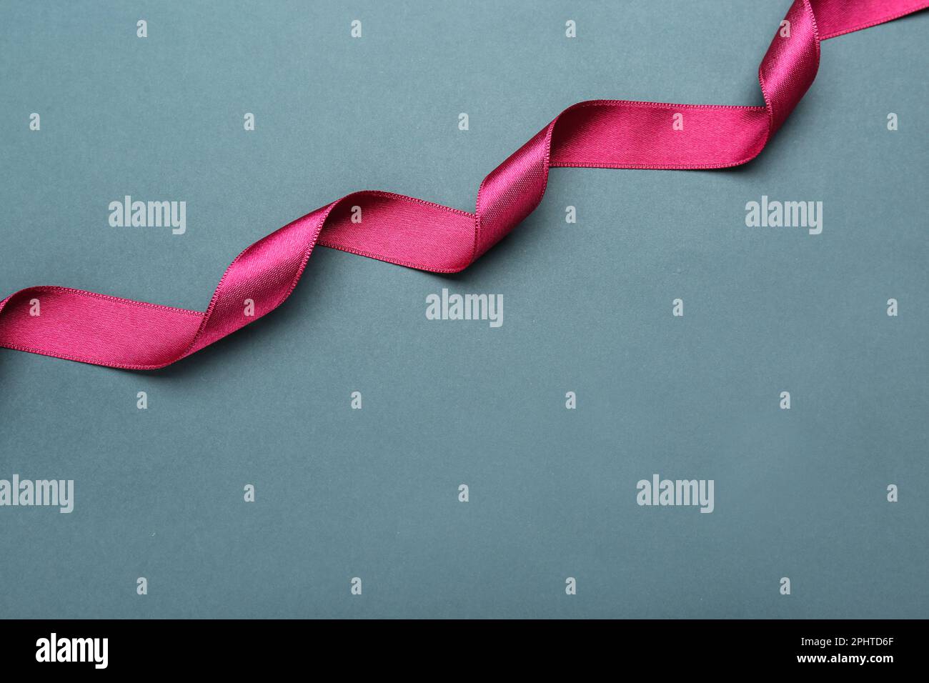 Beautiful pink ribbon on grey background, top view. Space for text ...