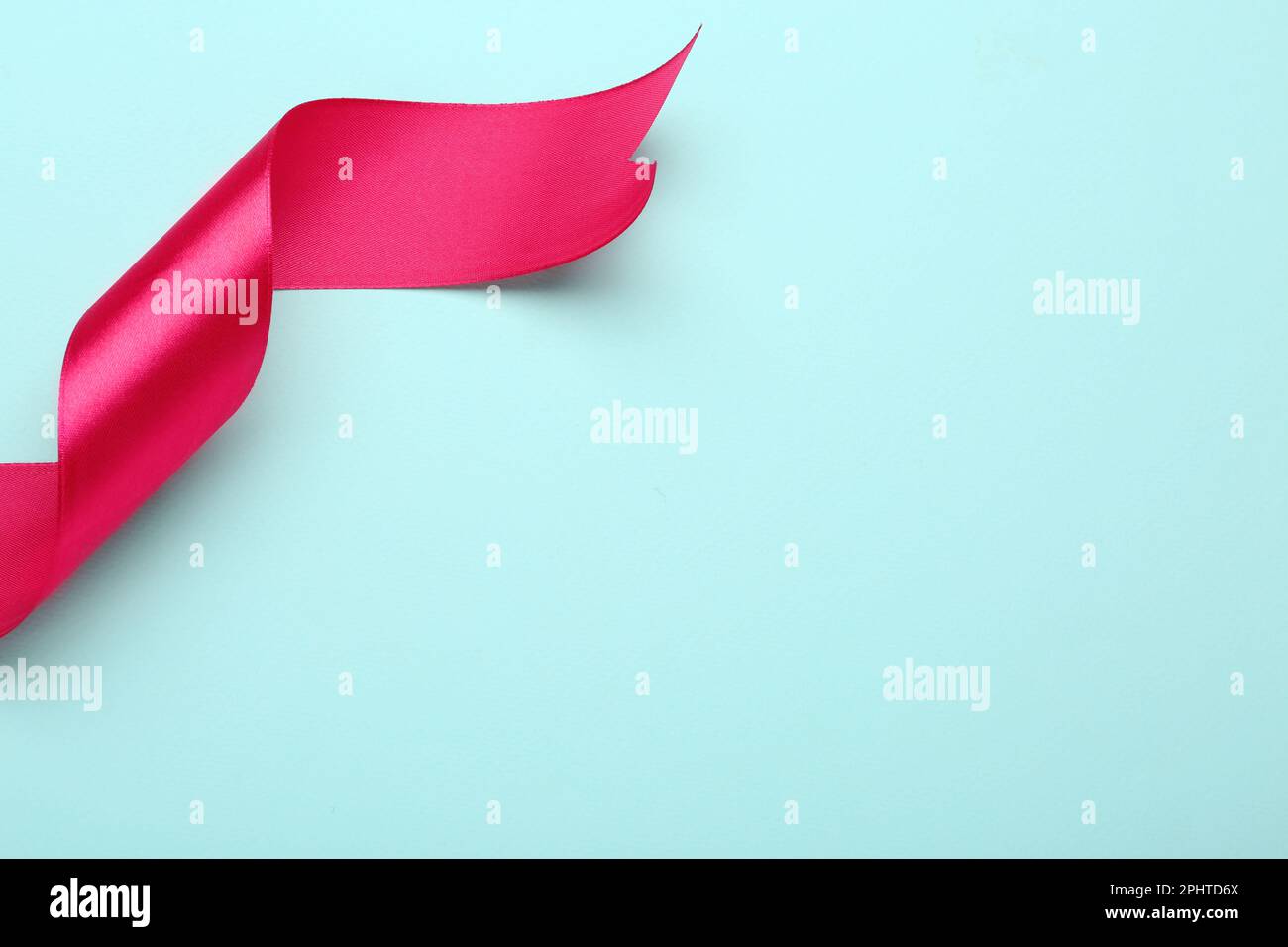 Beautiful pink ribbon on light blue background, top view. Space for ...