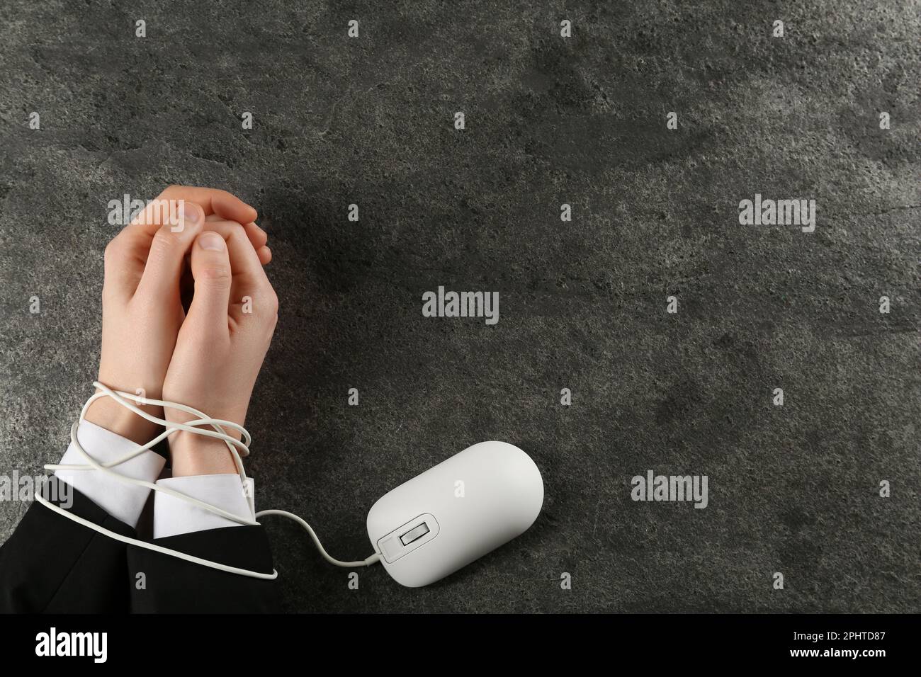 Man showing hands tied with computer mouse cable at grey table, top ...