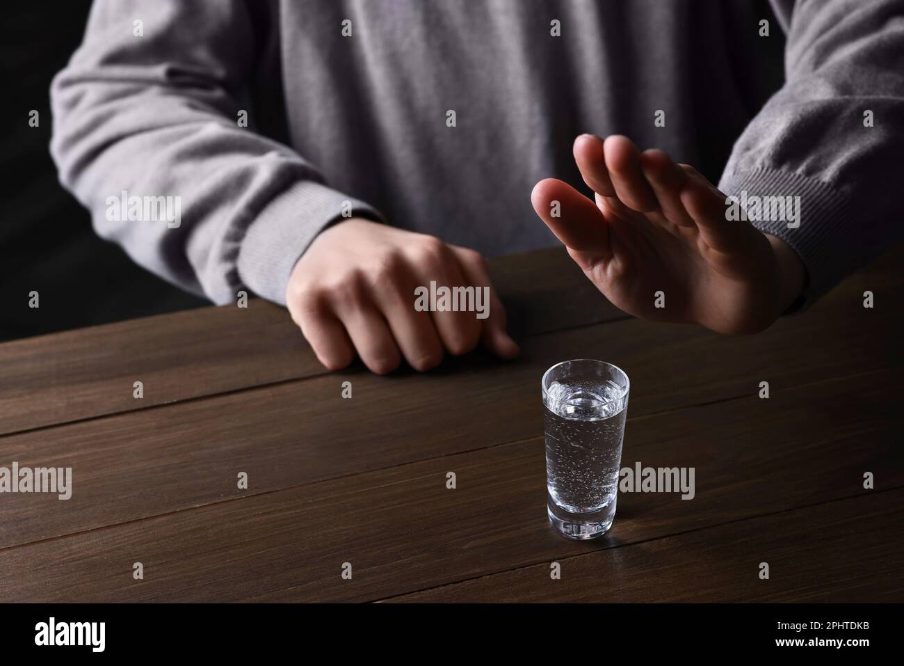 Man refusing to drink vodka at wooden table, closeup. Alcohol addiction ...