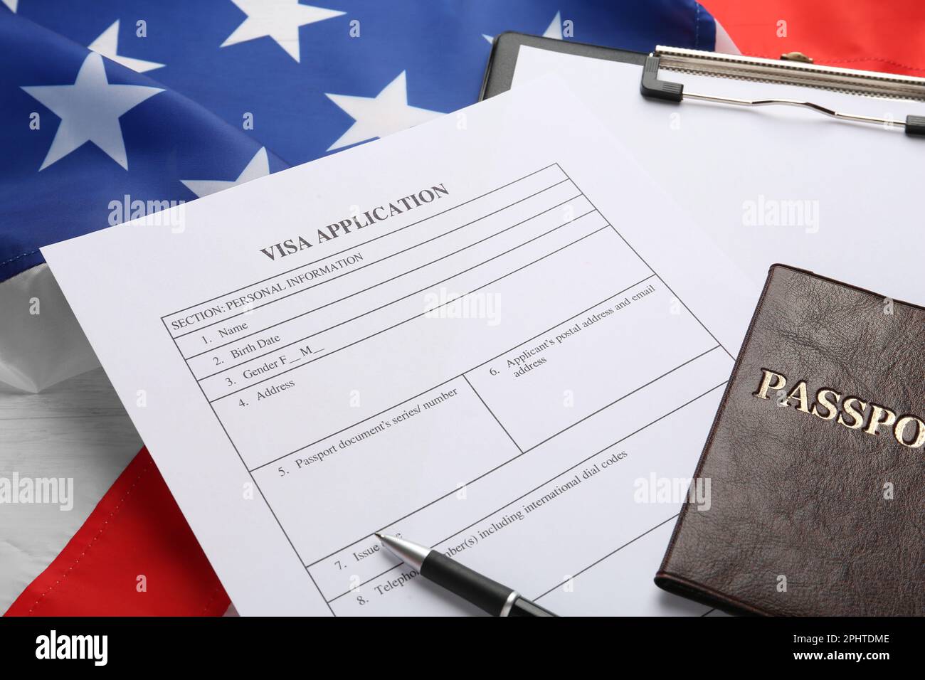 Visa application form, clipboard and passport on American flag, closeup ...