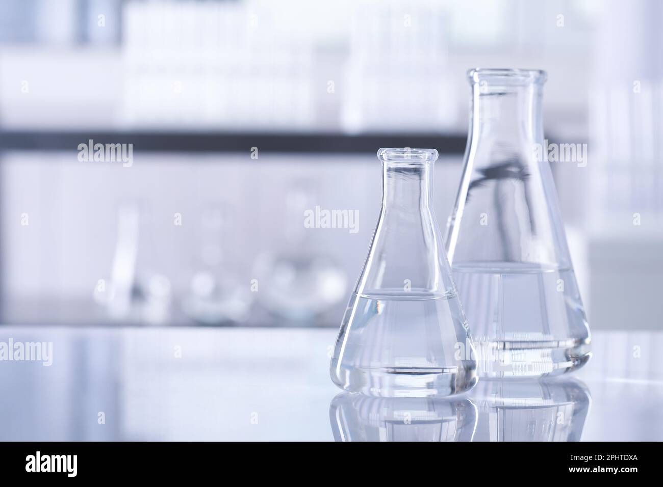 Conical flasks with transparent liquid on table in laboratory. Space ...