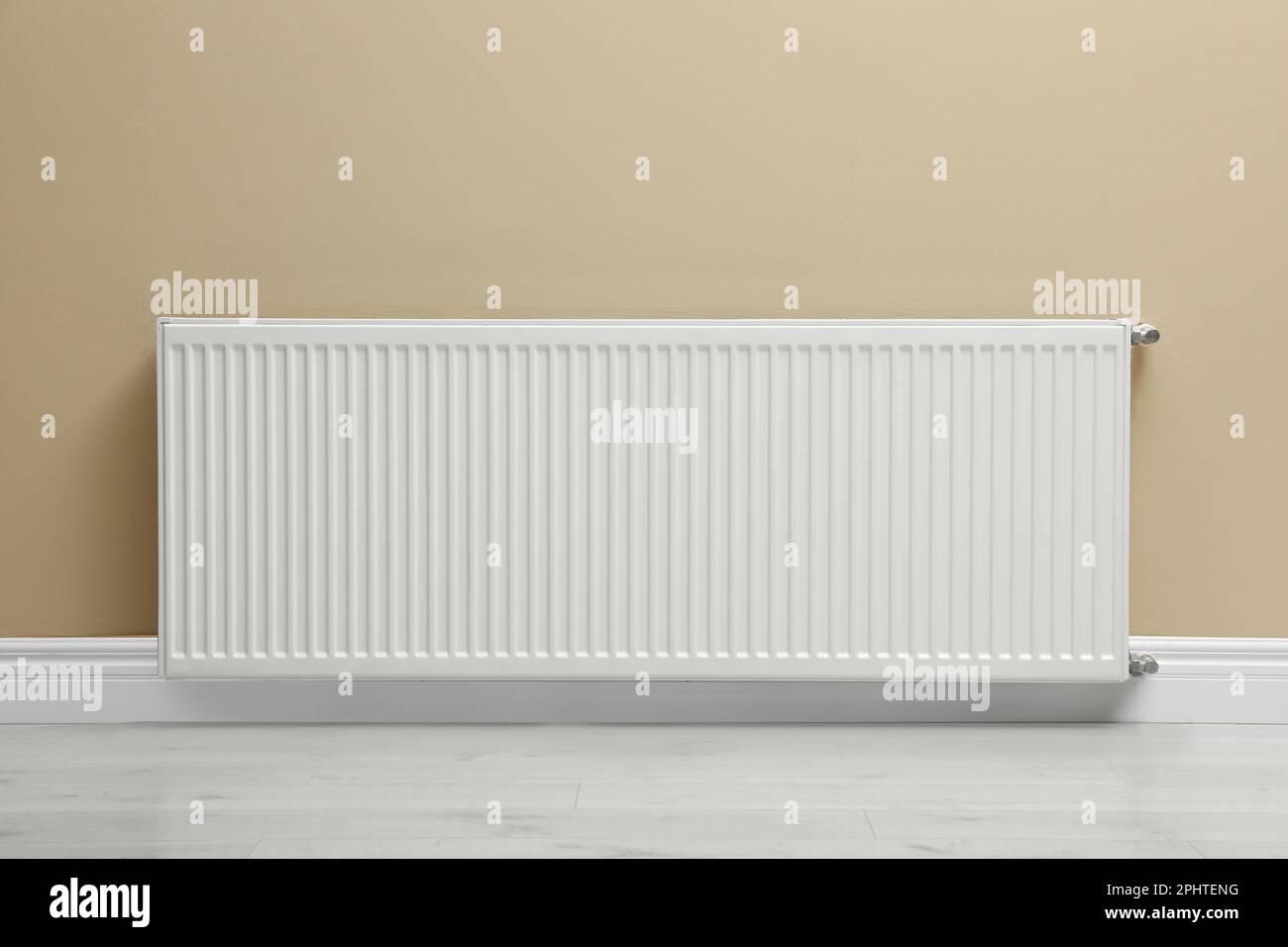 Modern radiator on beige wall indoors. Central heating system Stock ...