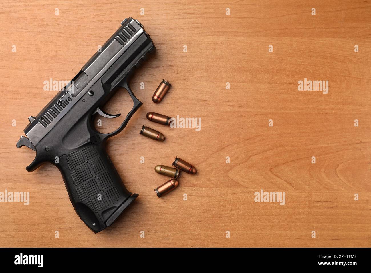 Semi-automatic pistol and bullets on wooden table, flat lay. Space for ...