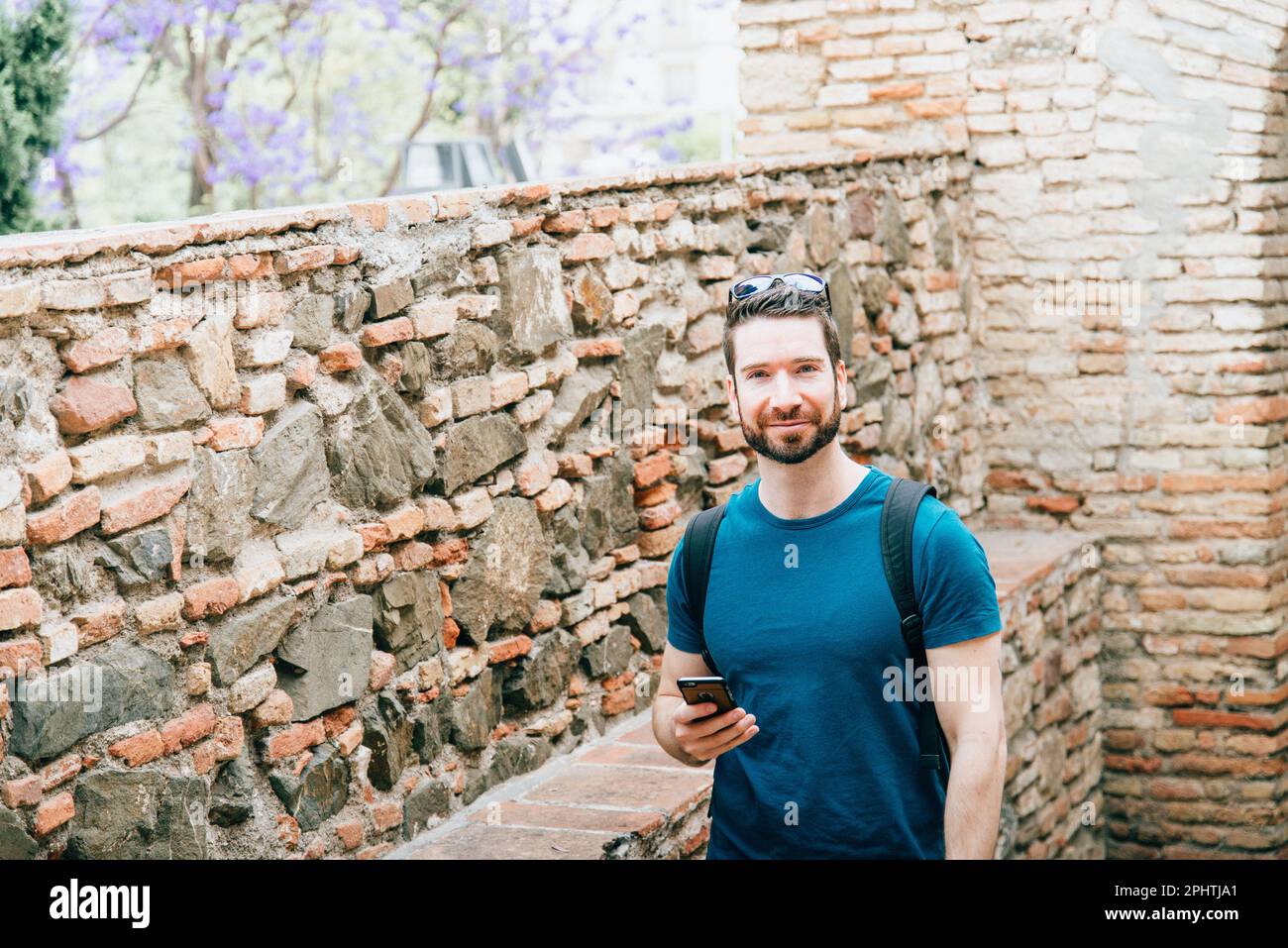 Young man traveller with a beard on a background of an old brick wall ...