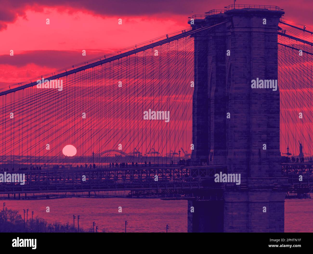 Sunset behind the Brooklyn Bridge with crowds of people gathered to ...