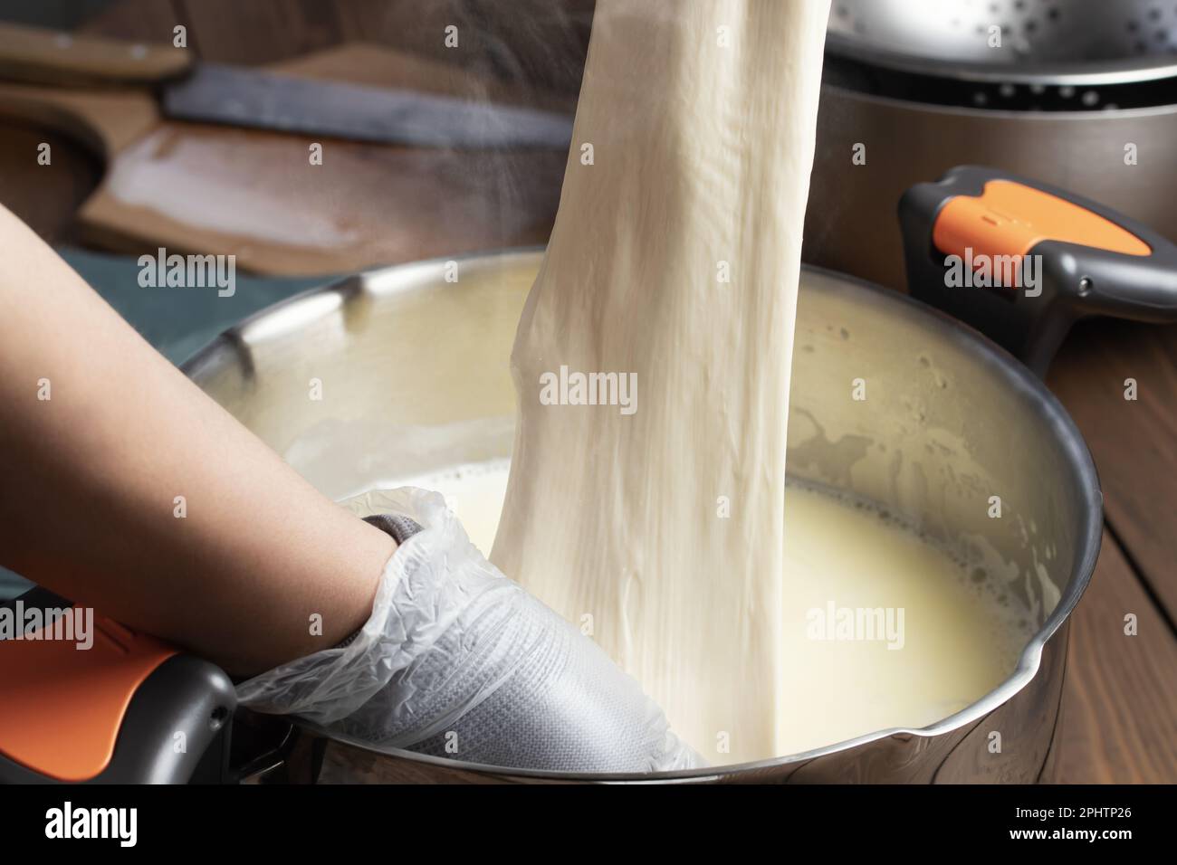 Making mozzarella cheese. Pulling out the cheese clot after heating in ...