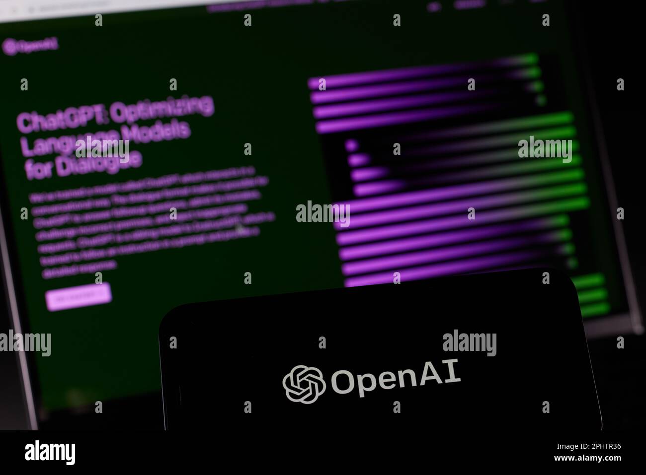 The logo of OpenAI is seen on a smartphone with a computer screen that ...