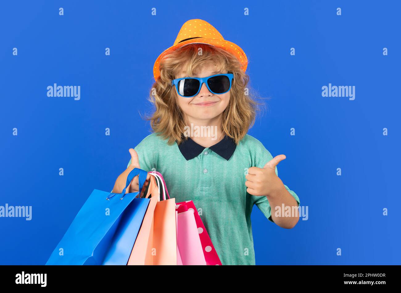 Child boy with many shopping bags in studio. Funny little kid in summer ...
