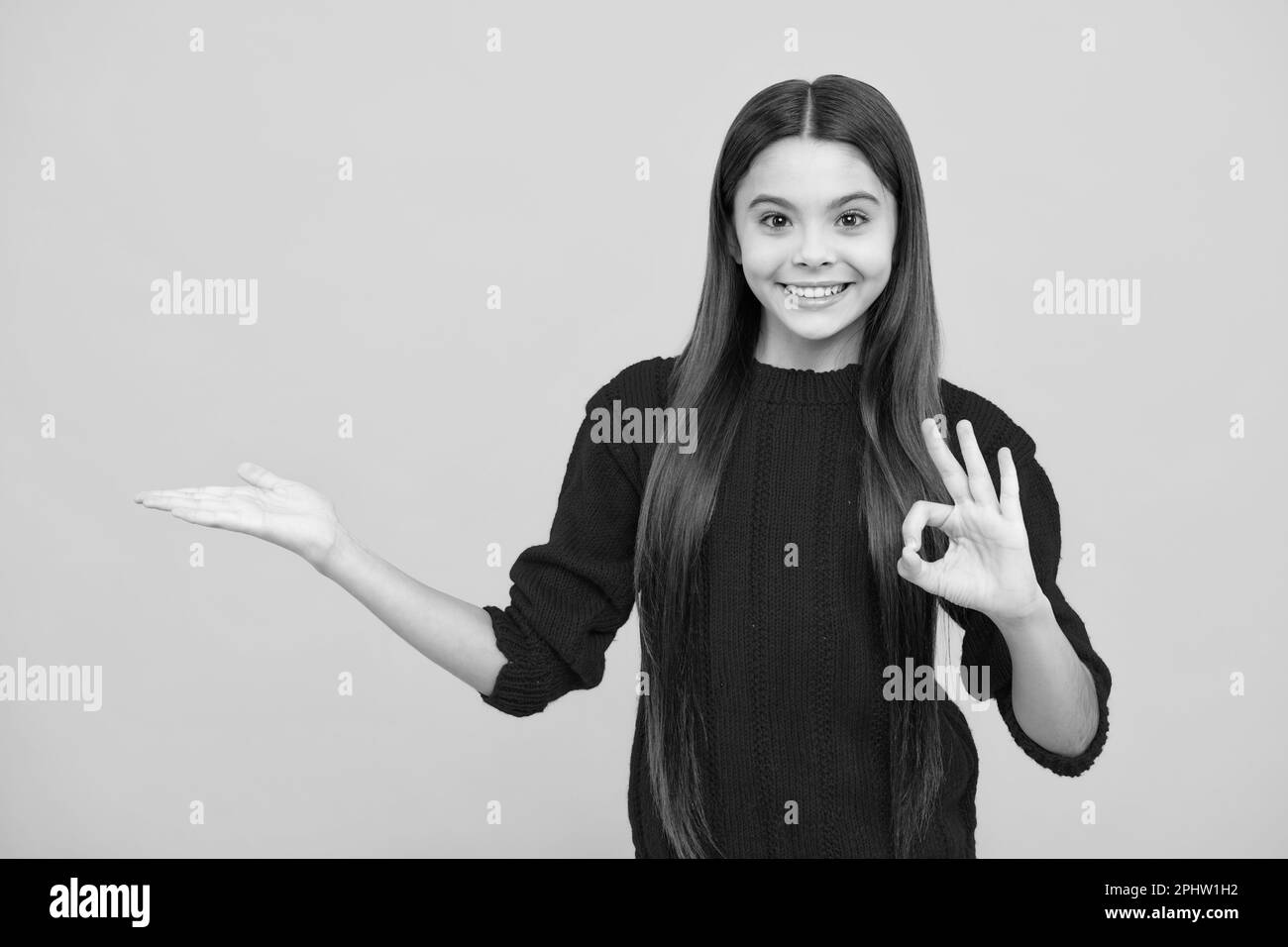 Positive teenager child points aside with cheerful expression, shows ...