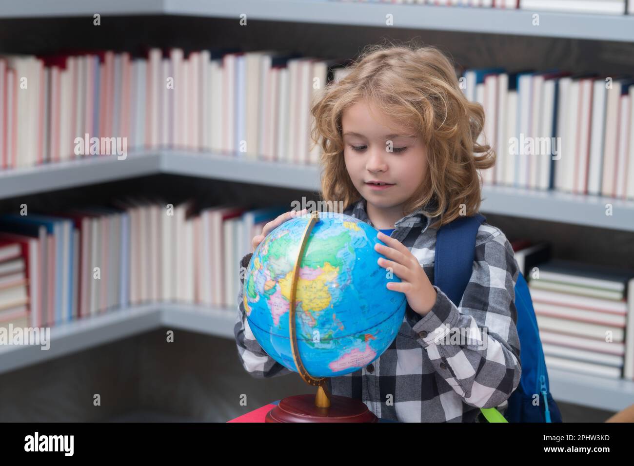 Explorer and discovery. School kid pupil looking at globe in library at the elementary school ...
