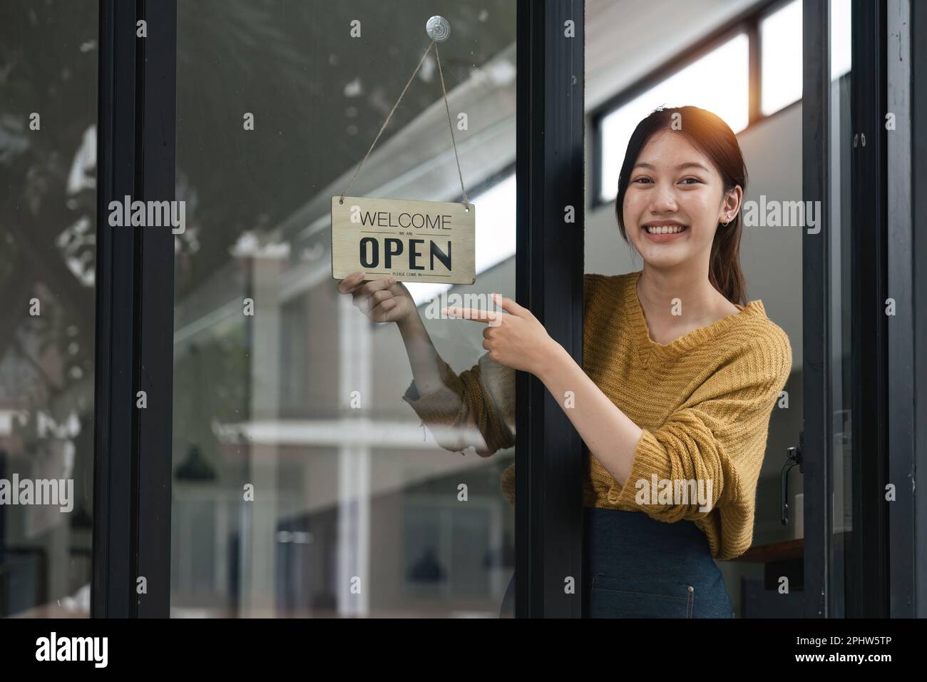 Young woman is a waitress in an apron, the owner of the cafe stands at ...
