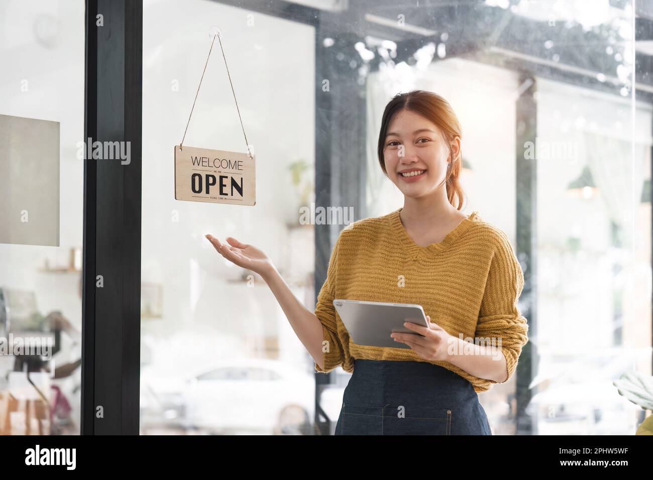 Young woman is a waitress in an apron, the owner of the cafe stands at ...
