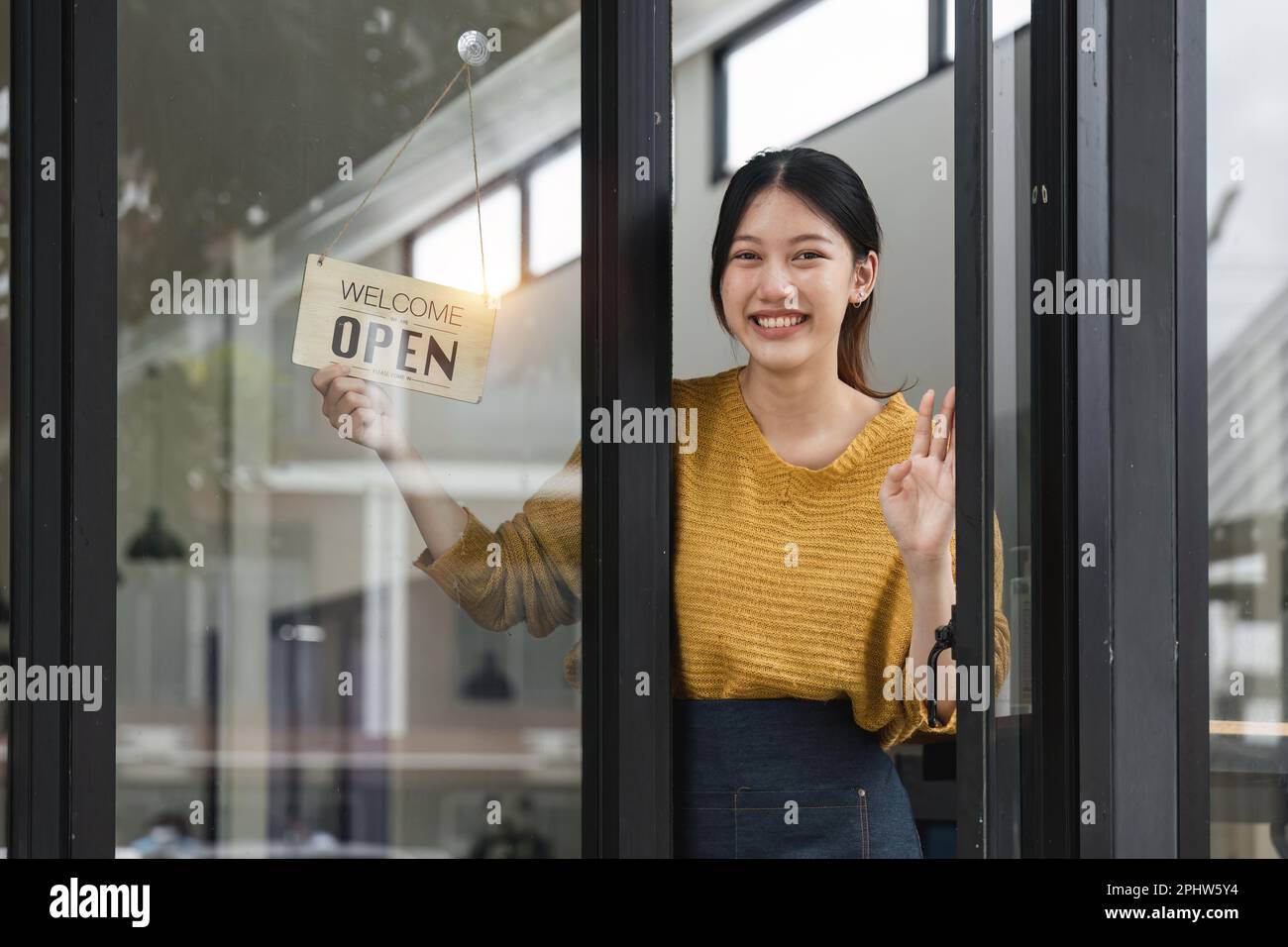 Young woman is a waitress in an apron, the owner of the cafe stands at ...