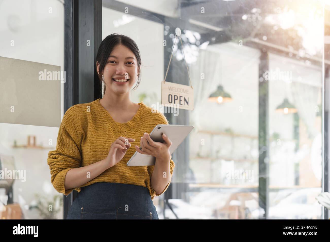 Young woman is a waitress in an apron, the owner of the cafe stands at ...