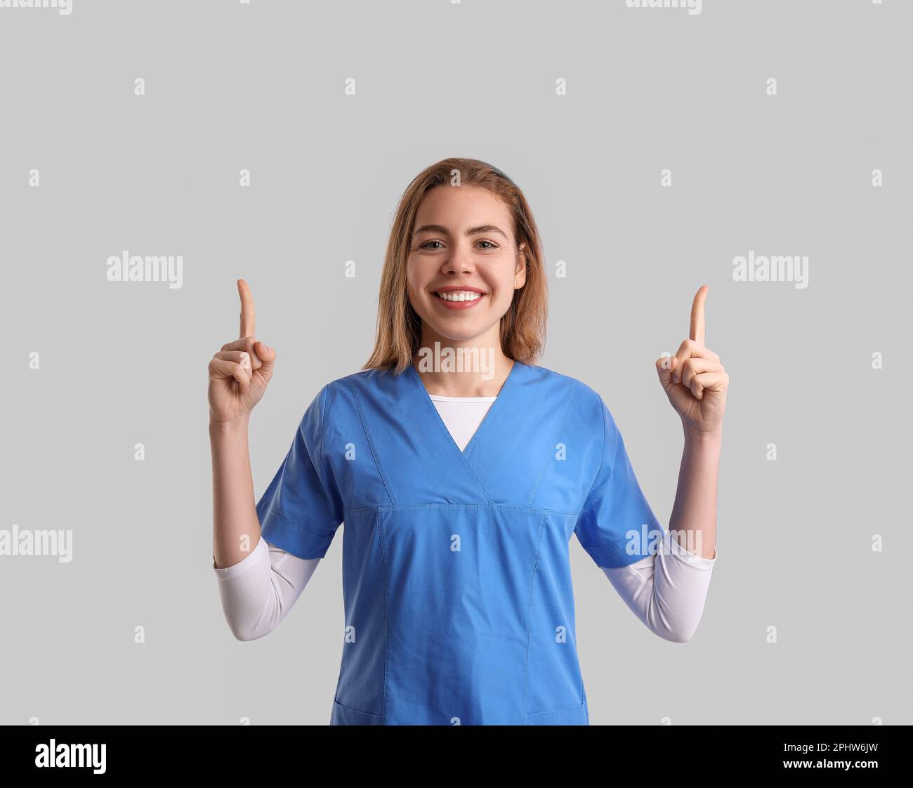 Female intern pointing at something on grey background Stock Photo - Alamy