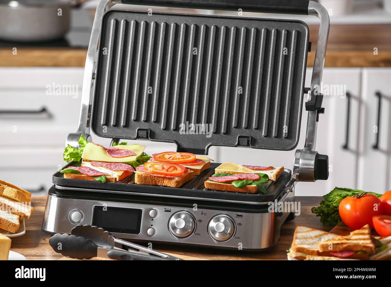 Modern electric grill with different delicious sandwiches on kitchen ...