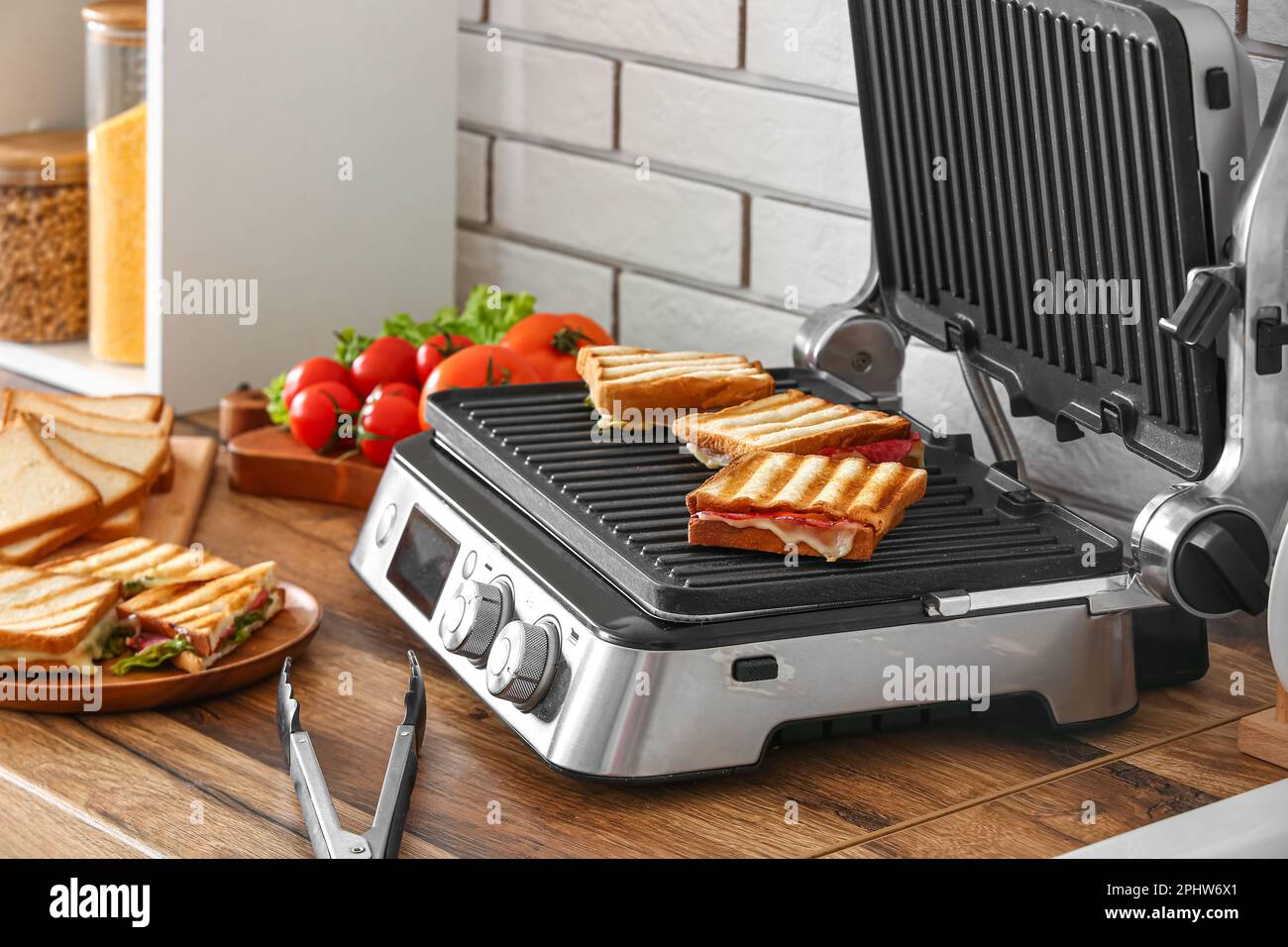 Modern electric grill with delicious sandwiches on kitchen counter ...