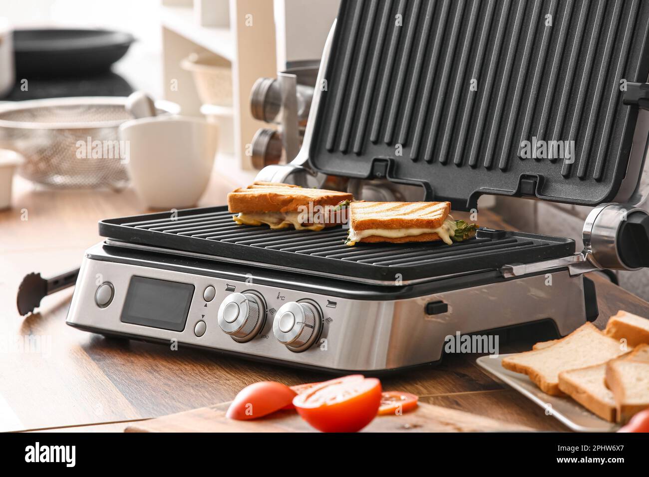 Modern electric grill with sandwiches and ingredients on kitchen ...