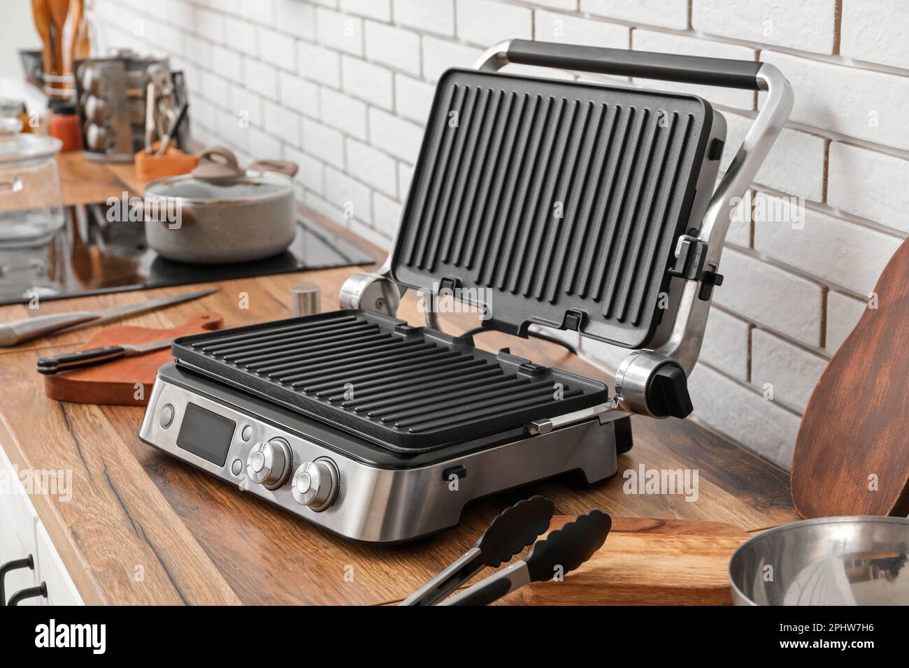 Modern electric grill on table near white brick wall Stock Photo - Alamy
