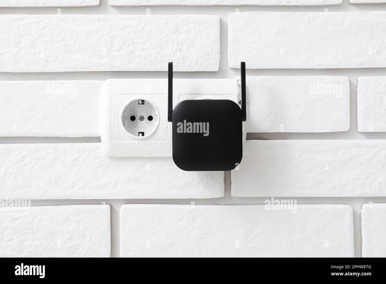 Black WiFi repeater in electric socket on white brick wall Stock Photo ...