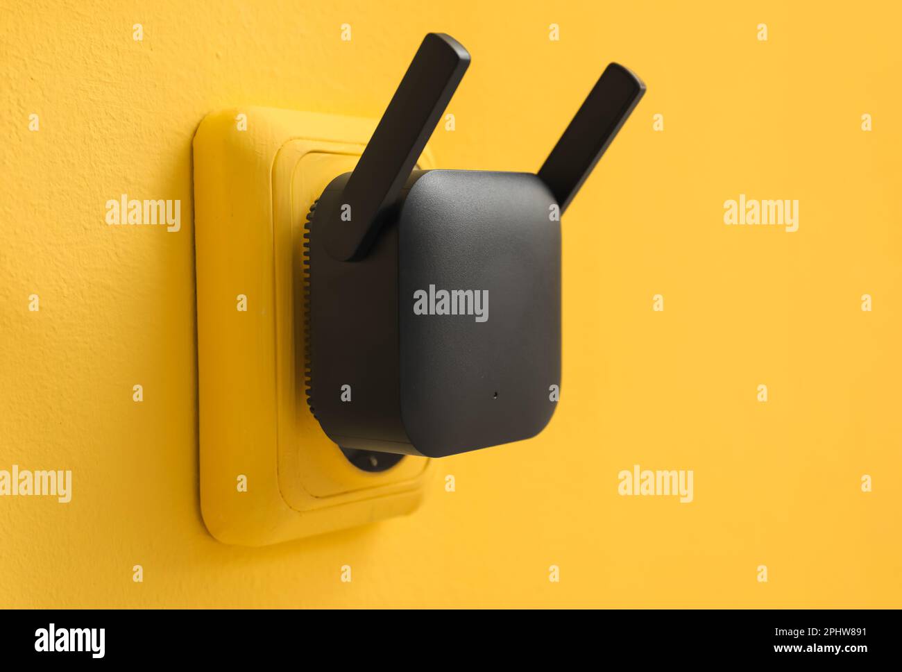 Black WiFi repeater in electric socket on yellow wall Stock Photo - Alamy