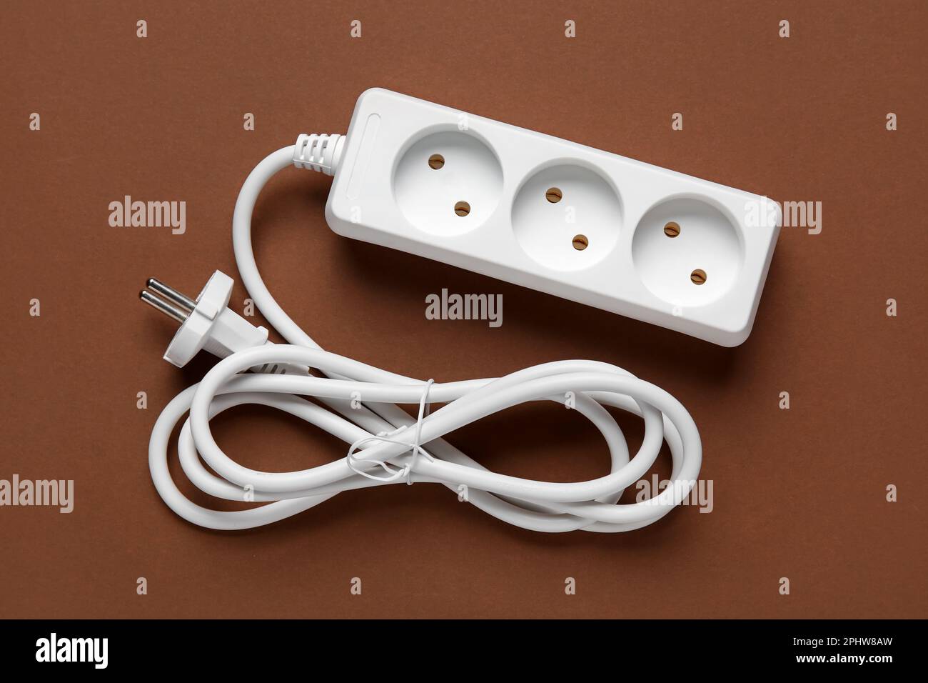 Electric extension cord on brown background Stock Photo - Alamy