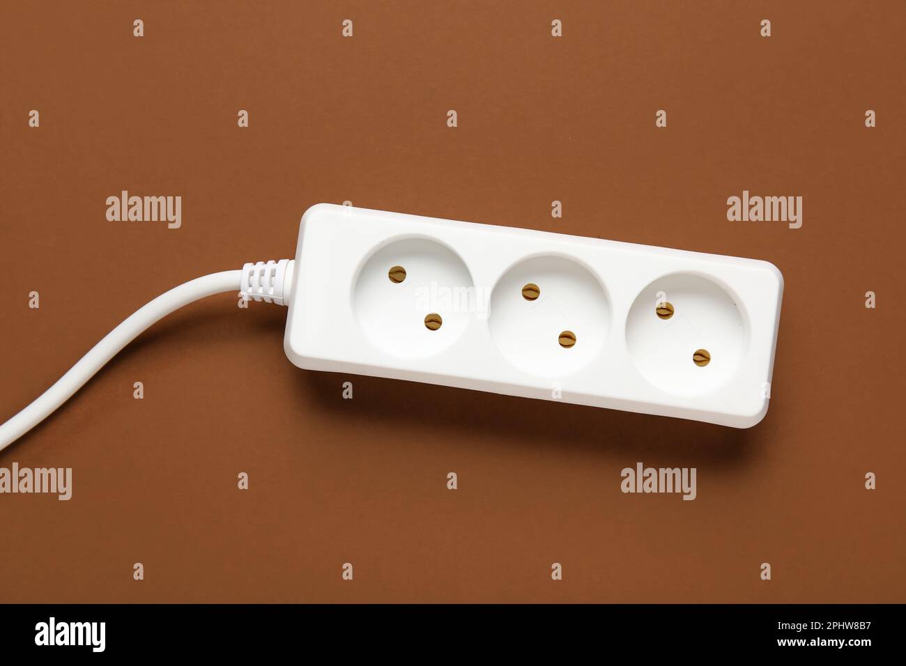 Electric extension cord on brown background Stock Photo - Alamy