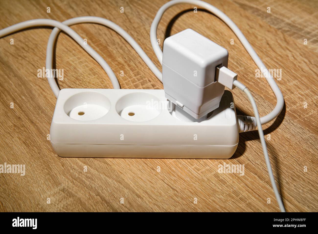 Electric extension cord with plug on wooden floor Stock Photo - Alamy