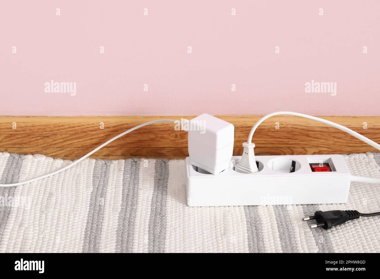 Electric extension cord with plugs on carpet near pink wall Stock Photo ...