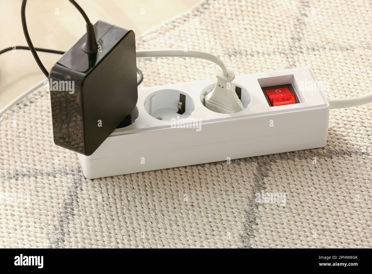 Electric extension cord with plugs on carpet Stock Photo - Alamy