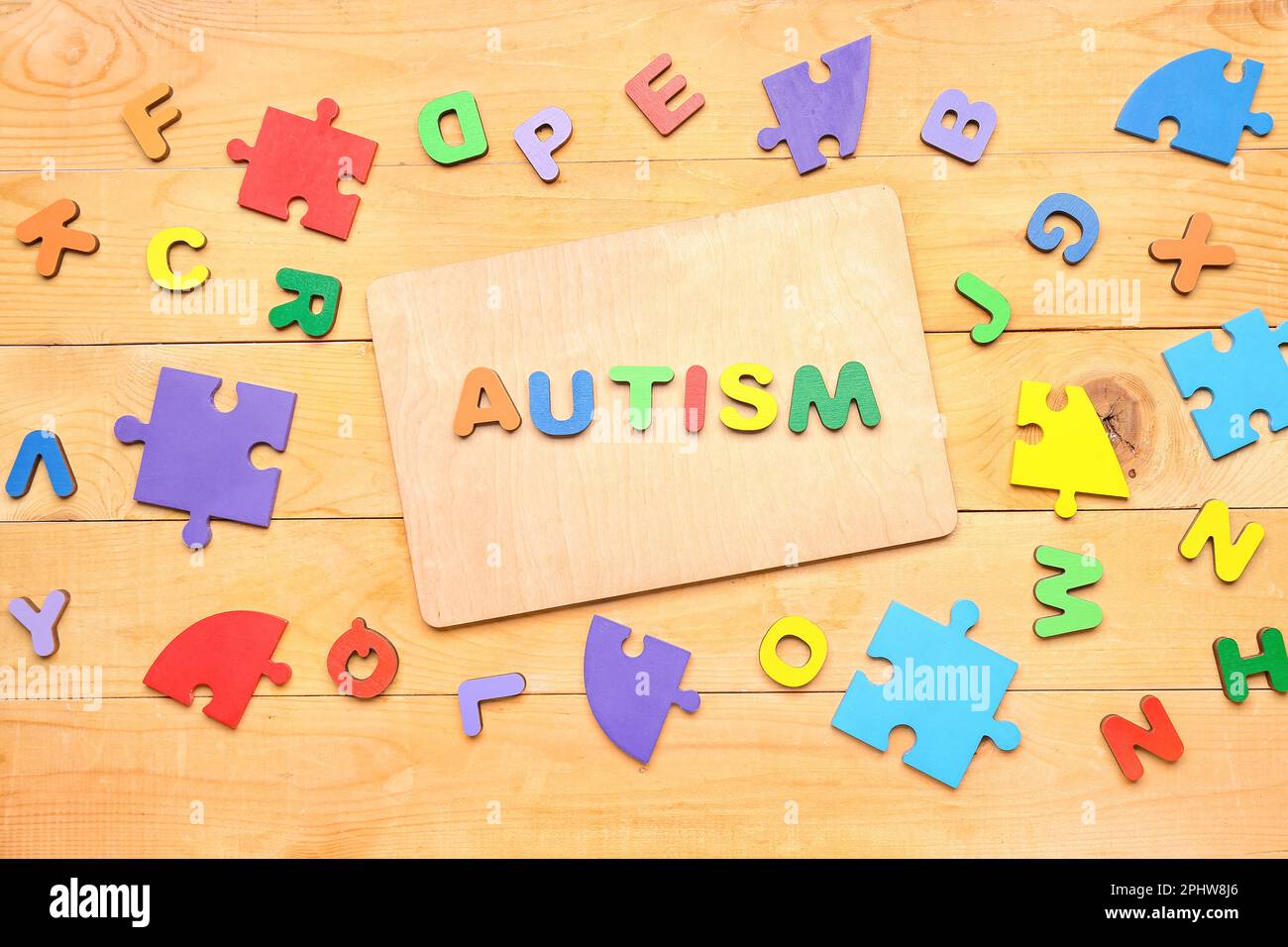 Word AUTISM with letters and puzzle pieces on wooden background Stock ...