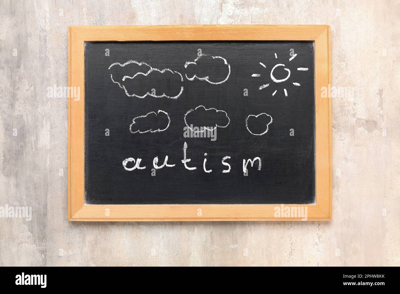 Chalkboard with word AUTISM, drawn clouds and sun on grunge background ...
