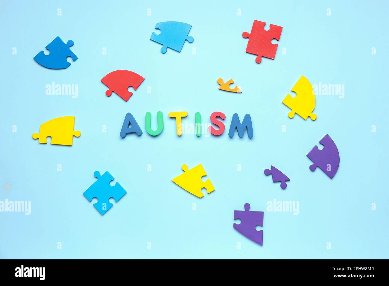 Word AUTISM with puzzle pieces on blue background Stock Photo - Alamy