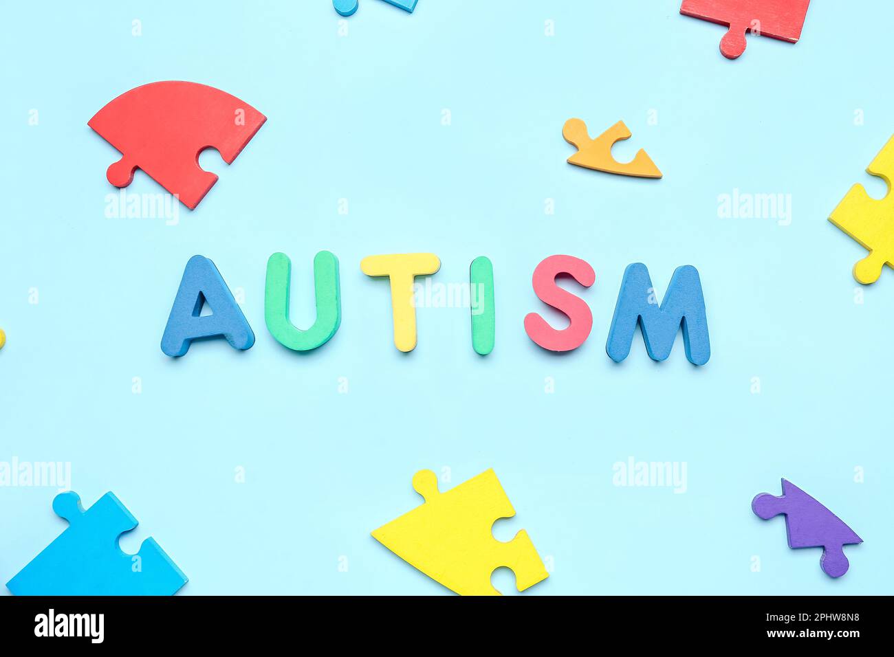 Word AUTISM with puzzle pieces on blue background Stock Photo - Alamy