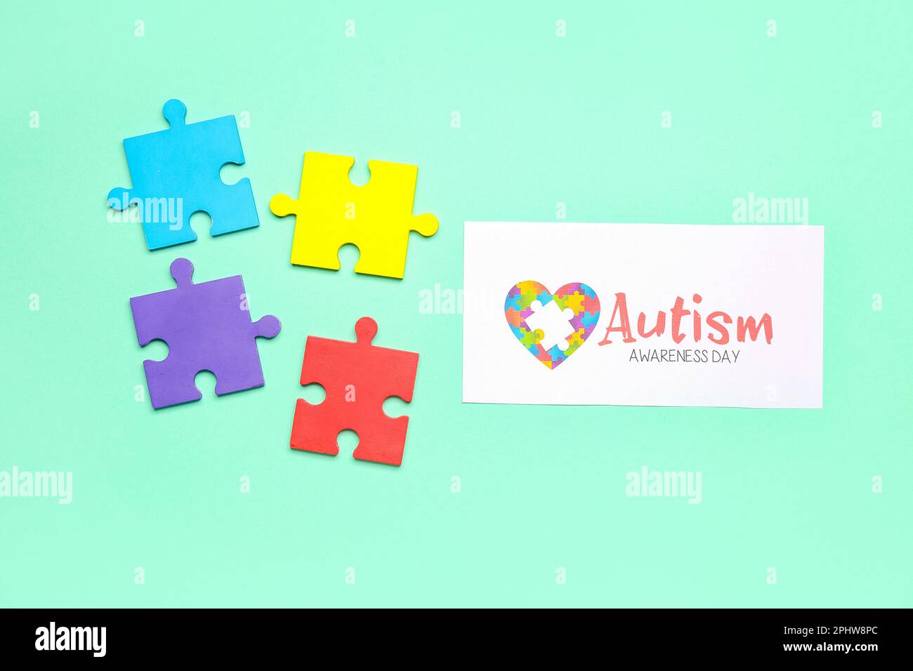 Paper with text AUTISM AWARENESS DAY and puzzle pieces on green ...