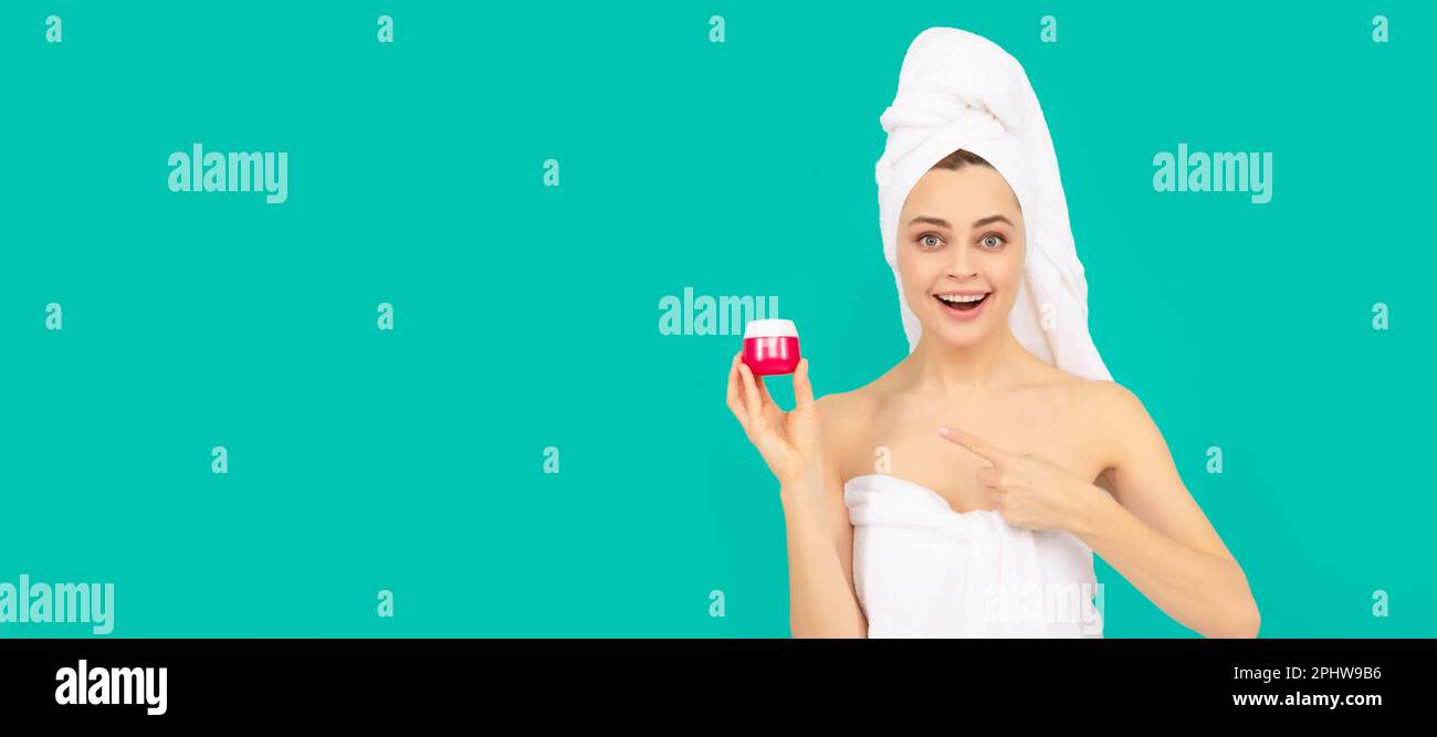 amazed girl in towel point finger on skin cream on blue background ...