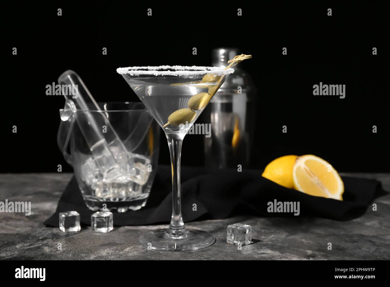 Glass of tasty martini with olives, ice cubes and lemon on dark ...