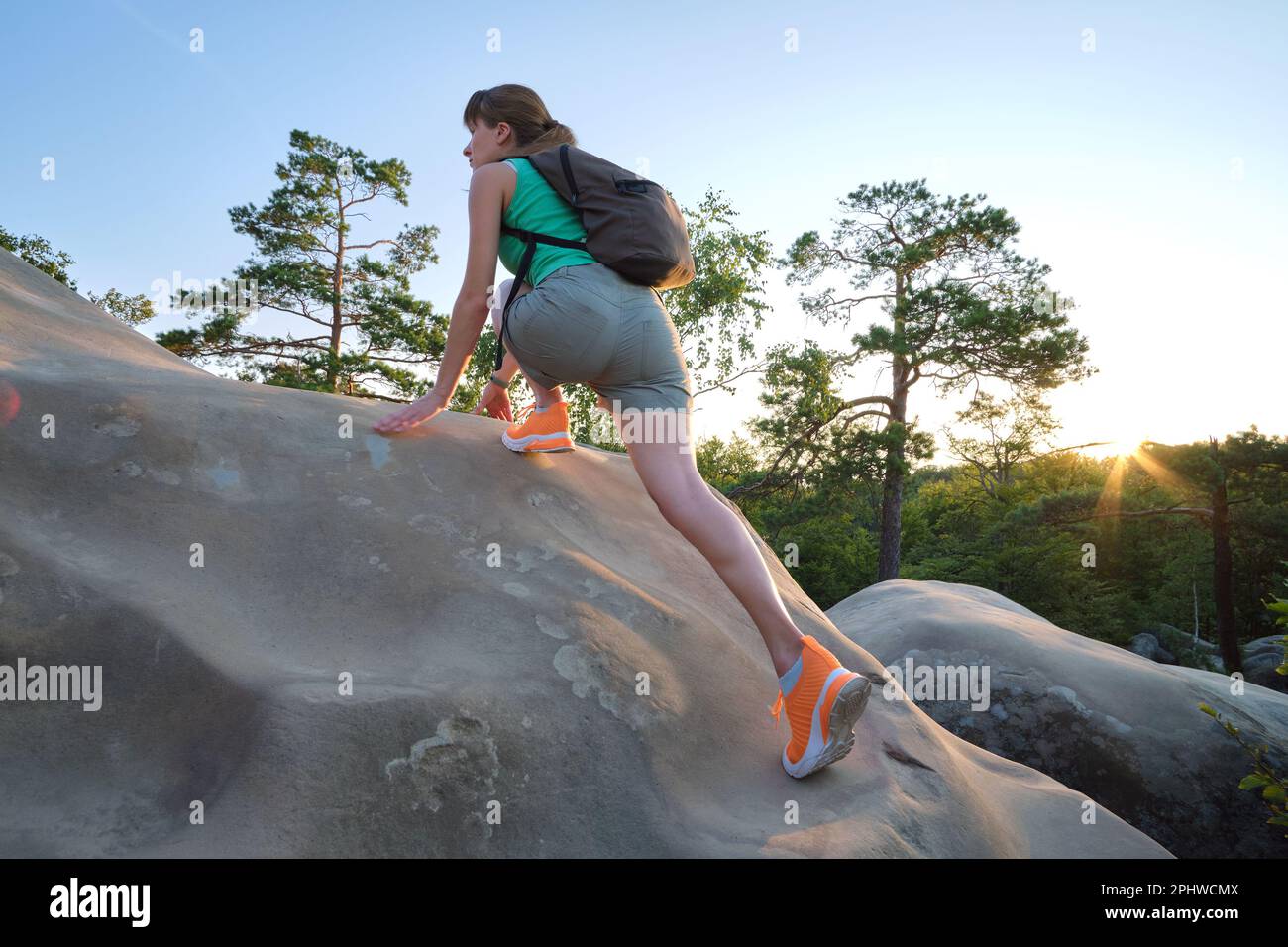 Sportive woman climbing alone on hillside rocky trail. Female hiker ...