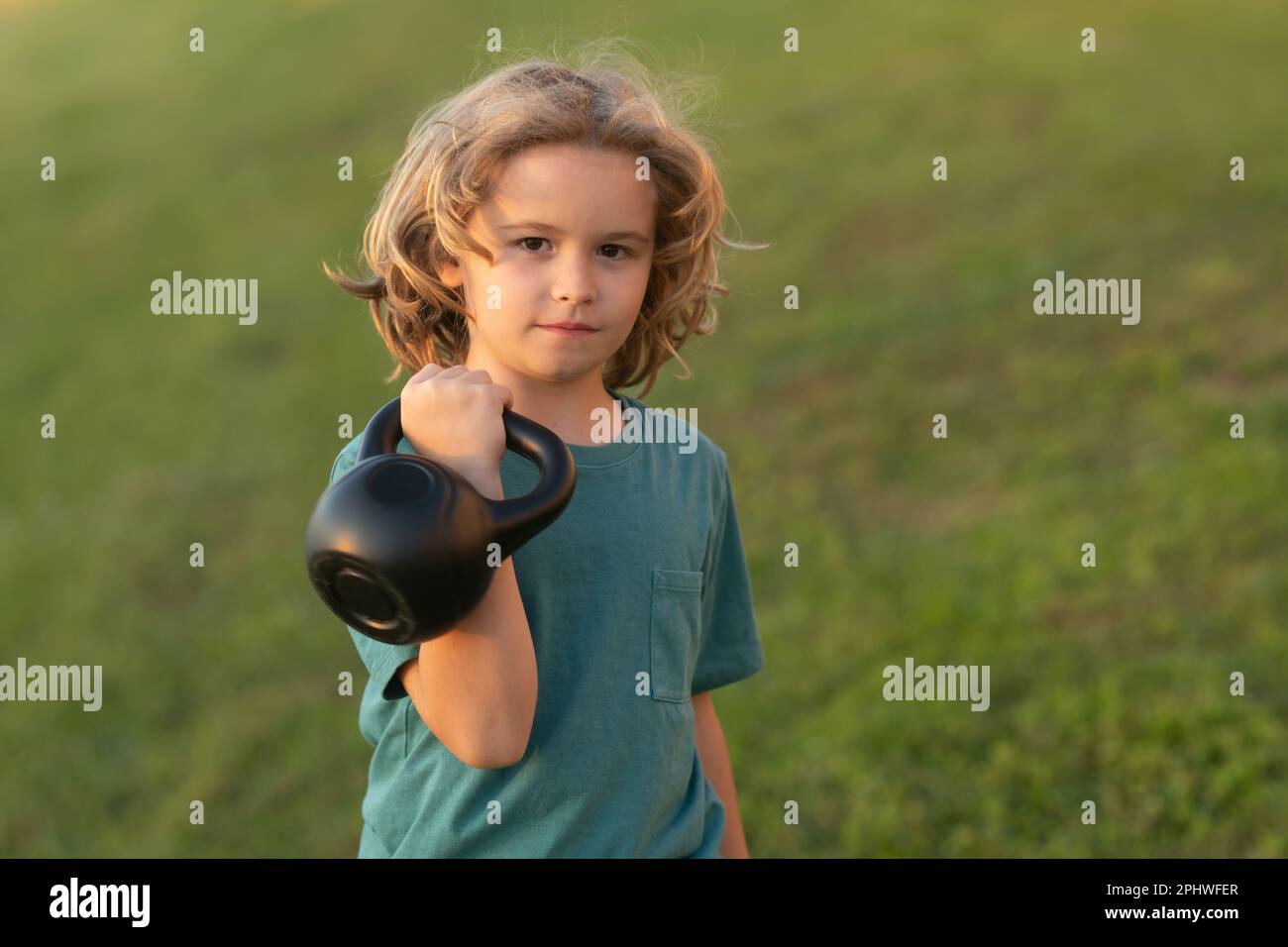 Kid raising a kettlebell. Cute child training with dumbbells. Kids ...