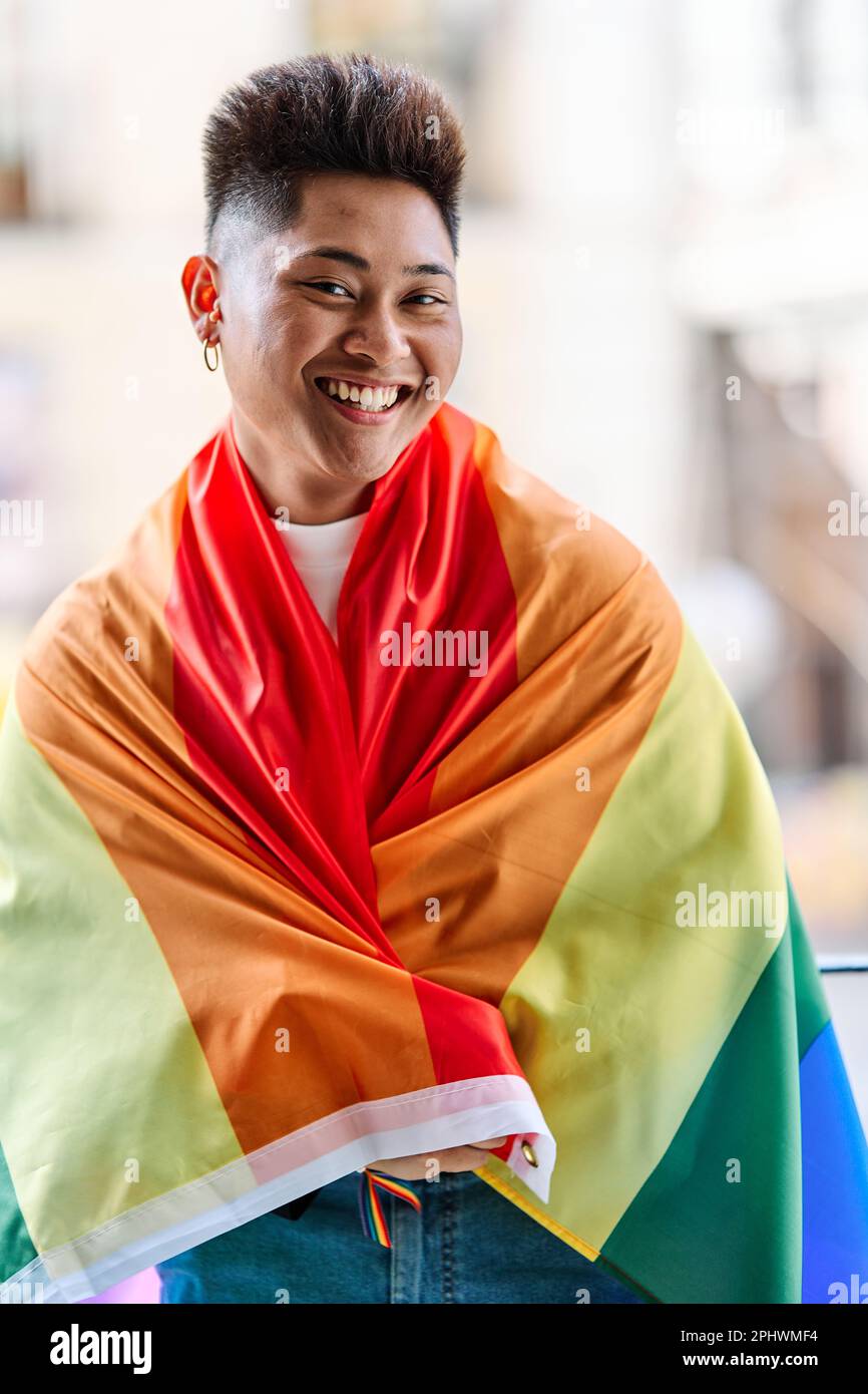 Happy gay man wrapping with a rainbow lgbt flag Stock Photo - Alamy