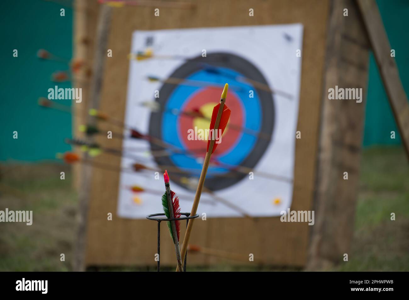 Colorful archery arrows in close up and unfocused target board in ...