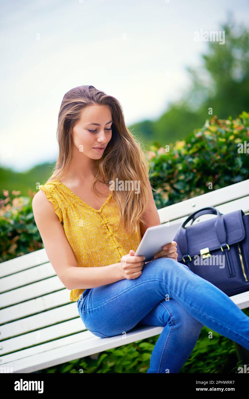 Taking the internet outdoors. a young woman using a digital tablet on a ...