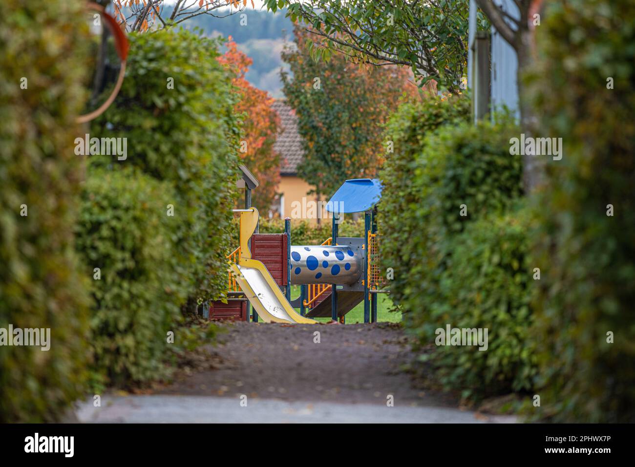 Colorful playground at the end of a walking path between hedges Stock ...