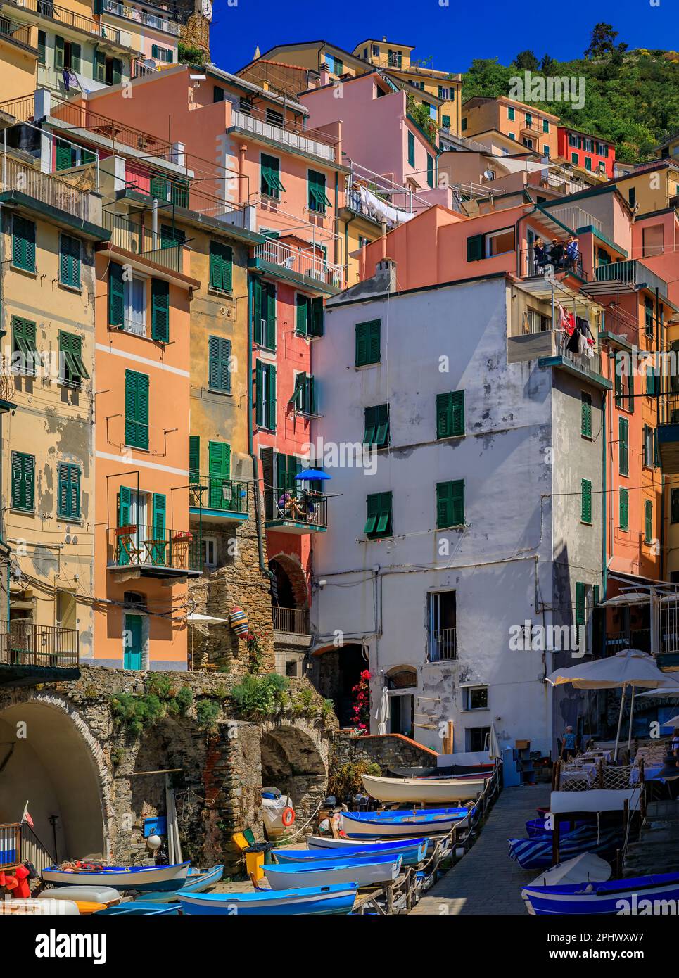 Traditional colorful houses on a hillside street and fishing boats in old town of Riomaggiore in ...