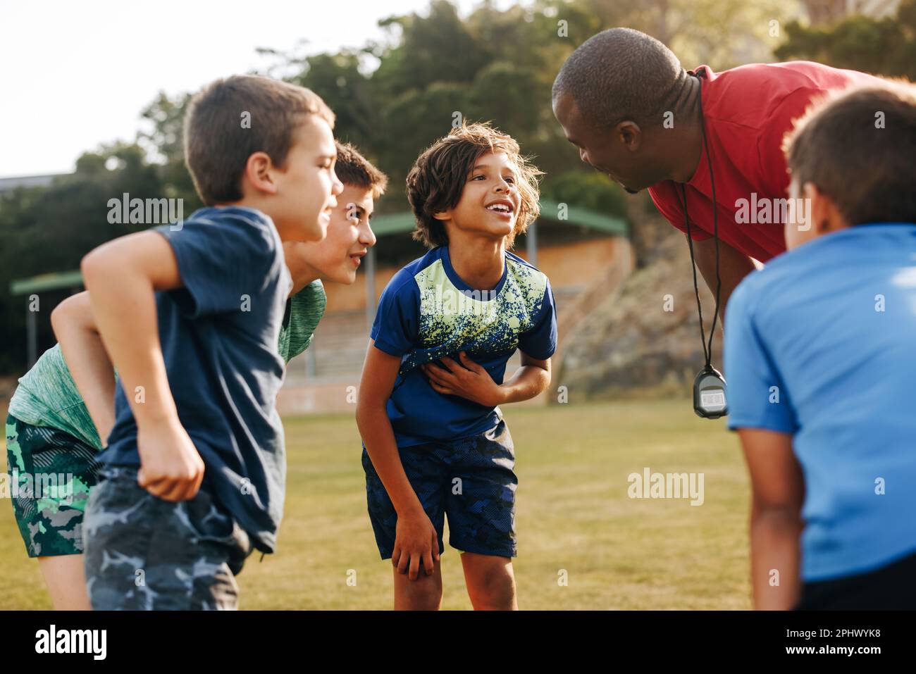 Team motivation in an elementary school ground. Sports coach having a ...