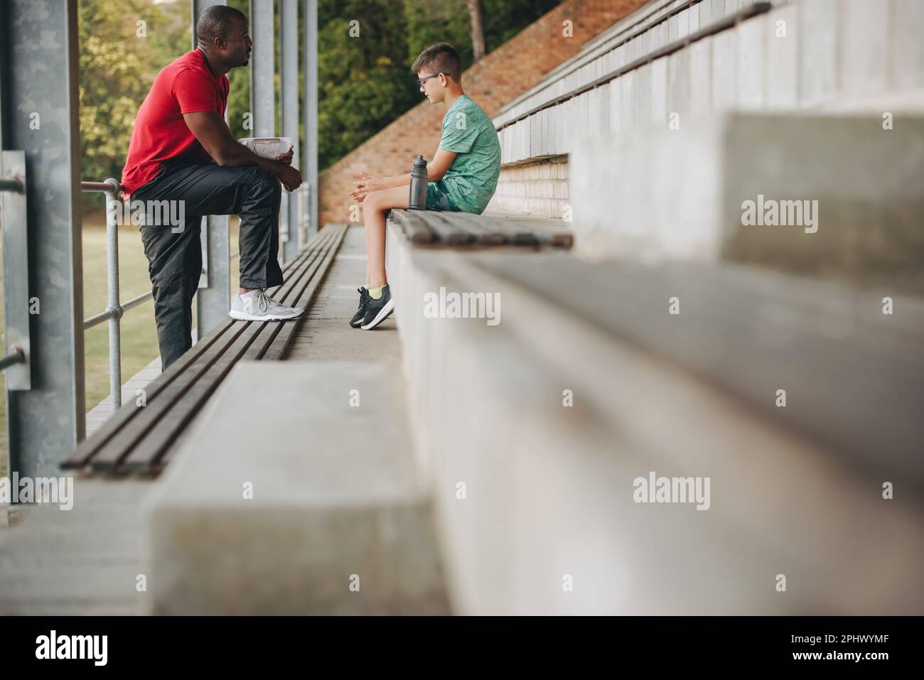 Coach motivating a sad school boy outdoors. Physical education teacher ...