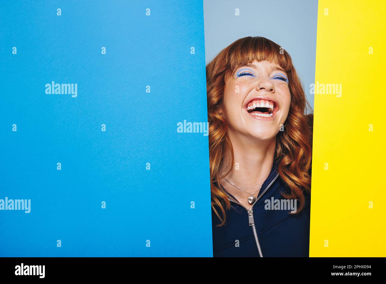 Young woman laughing while standing with two geometric shapes. Woman ...